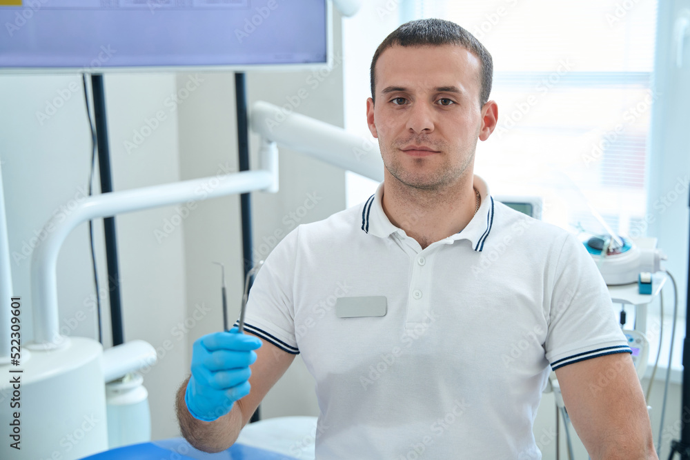 Professional male dentist showing diagnostic tools for oral cavity ...