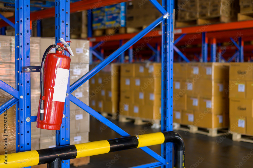 Fire extinguisher on shelf of cardboard boxes in modern warehouse ...