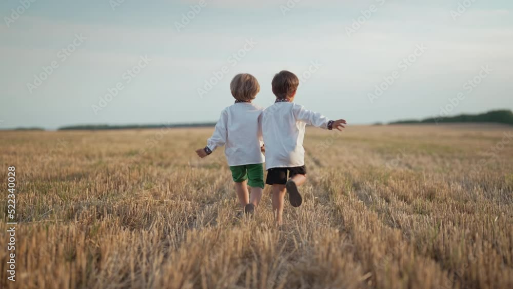 Two boys running together on open area wheat field after harvesting ...