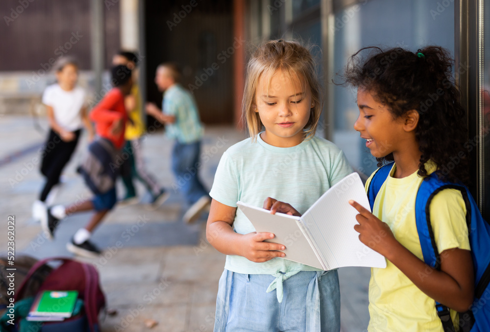 Poster Portrait of two primary school girls talking outside before ...