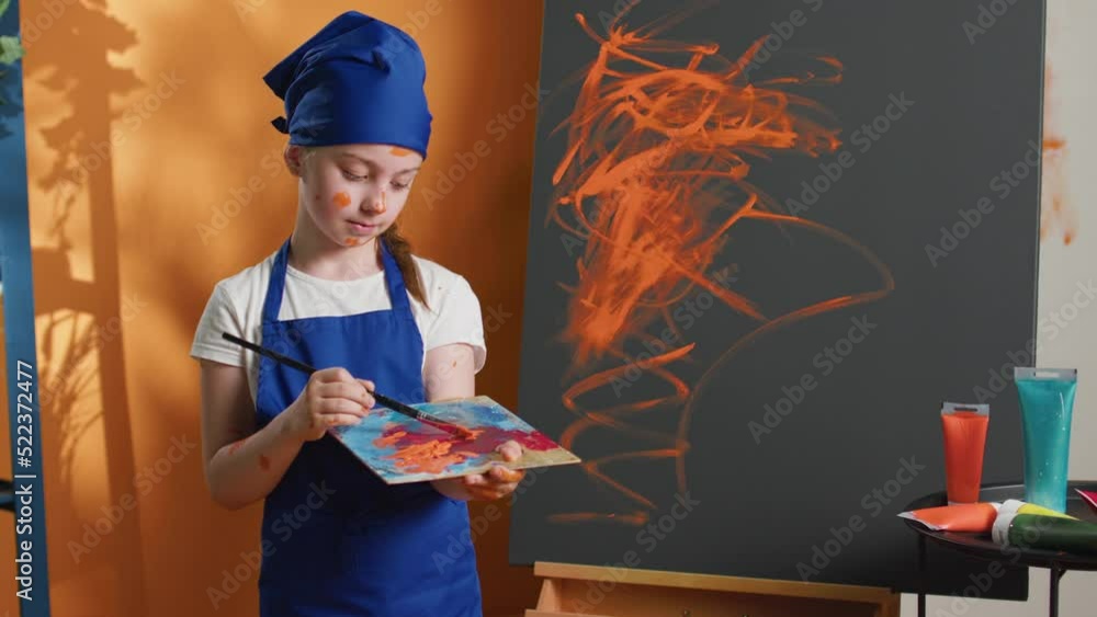 Vídeo do Stock: Portrait of young child using orange color paint on ...