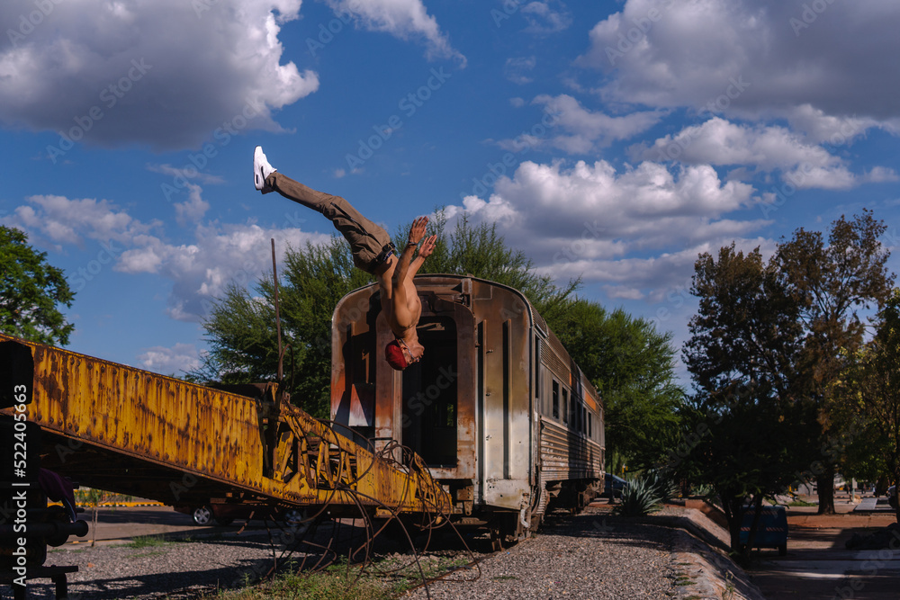 Boy in the middle of a jump backwards. Athletic young Latino man doing ...