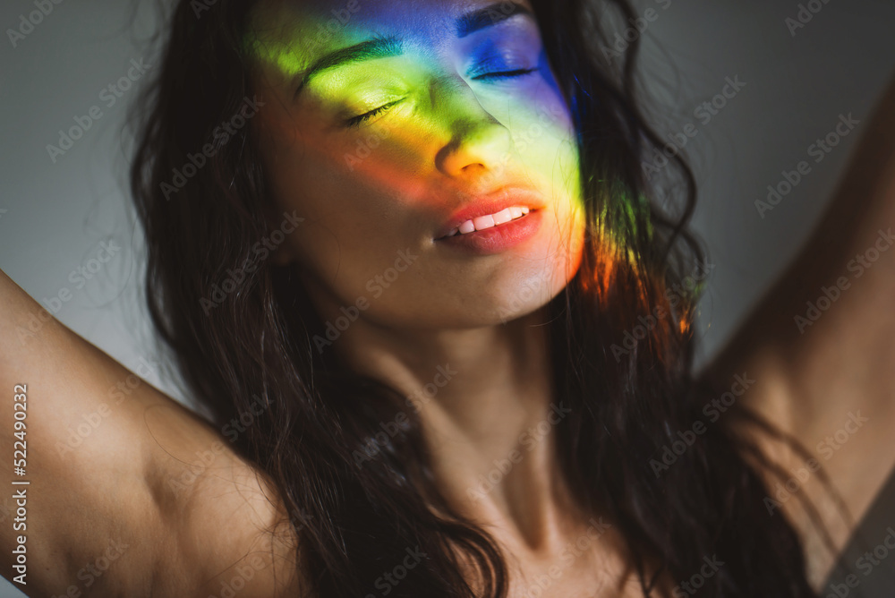 Closeup portrait of smiling woman with ray of rainbow light on her face ...