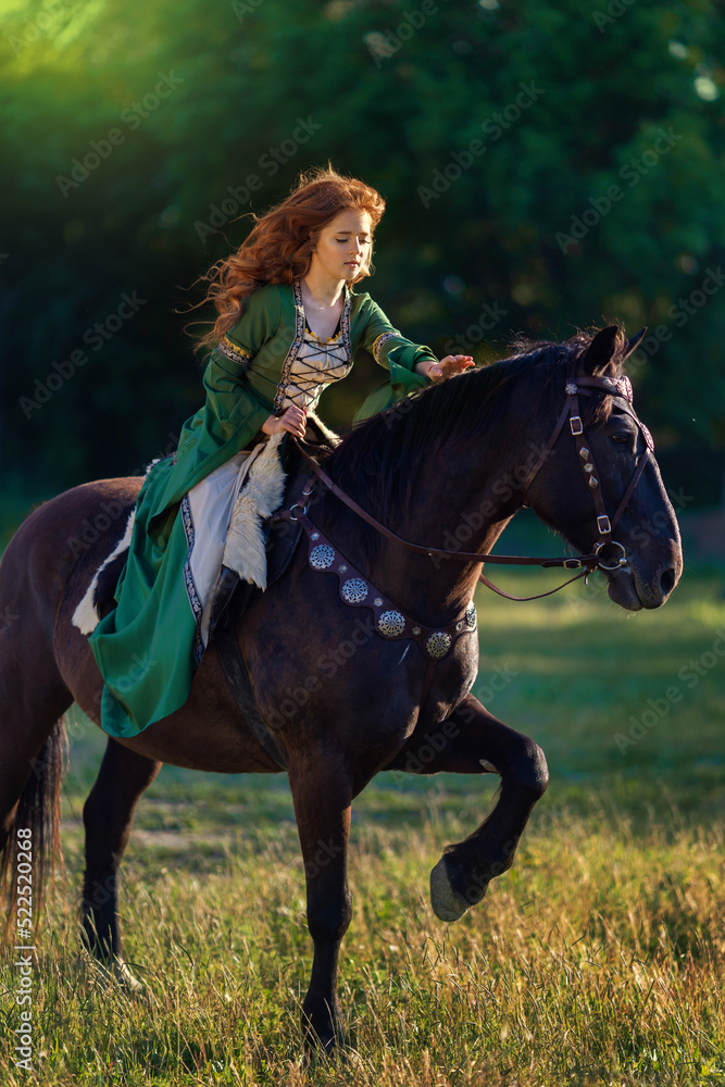 Medieval woman princess in green dress sits astride black steed horse ...