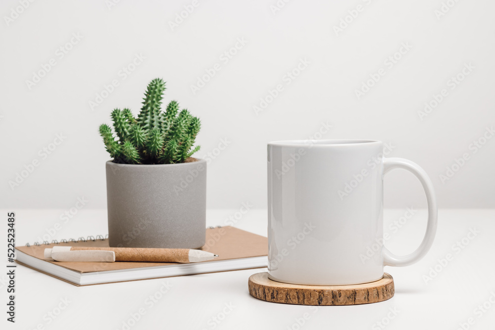 White mockup mug with notepad and cactus houseplant at the background ...