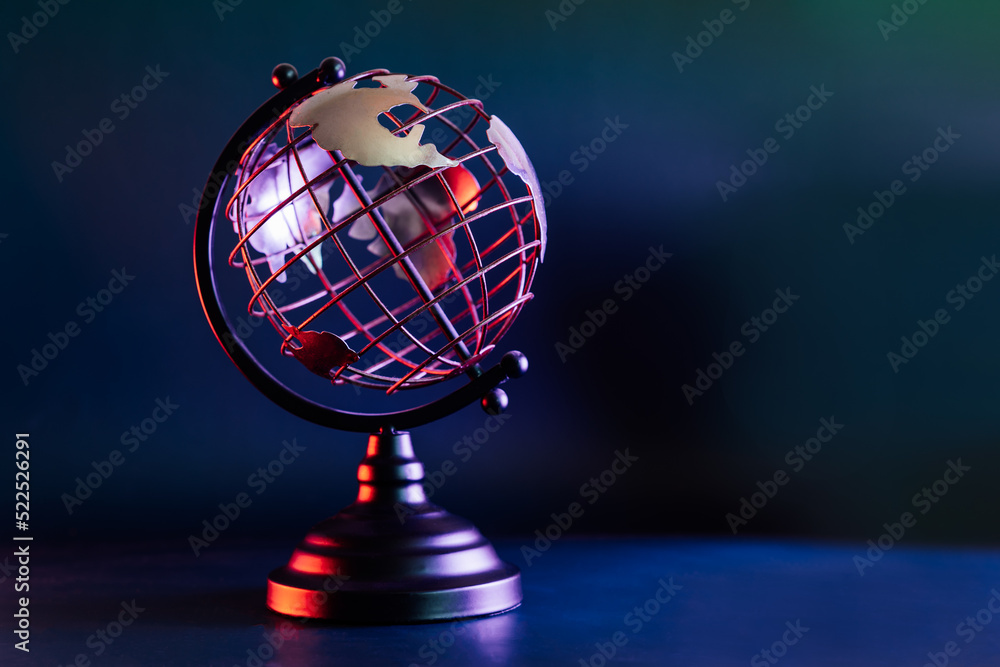 Metallic model of a globe with map in blue and red neon light ...