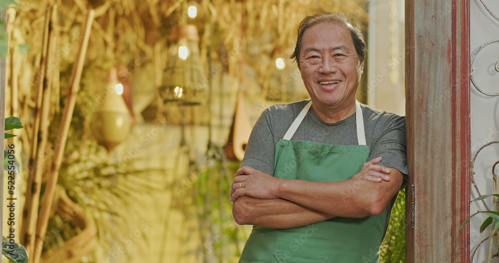 An Asian American business owner wearing apron and crossing arms ...