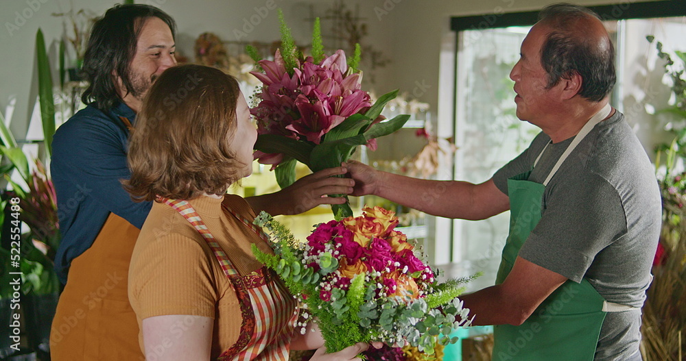 Flower shop employees holding flowers in conversation. A Happy local ...