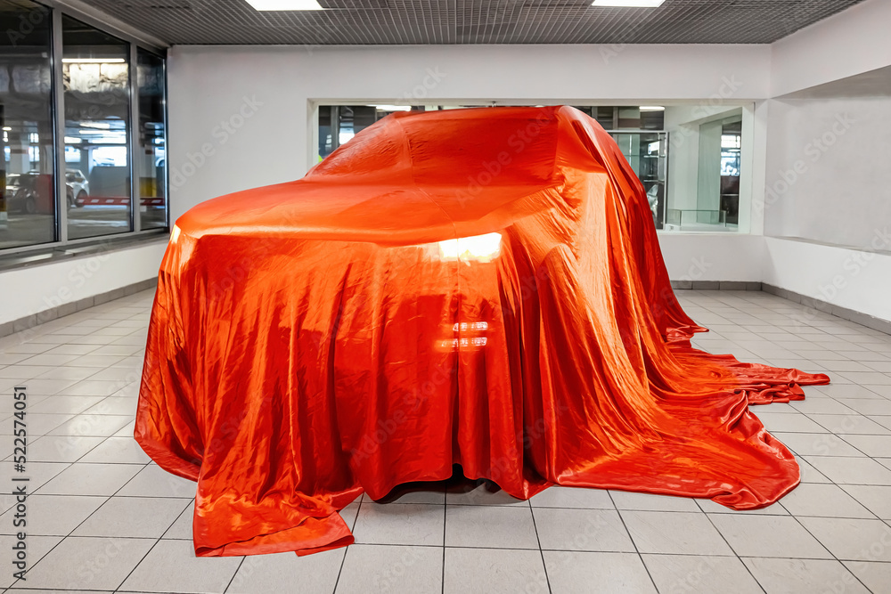 New car as a gift. The car is covered with a red cloth. surprise ...