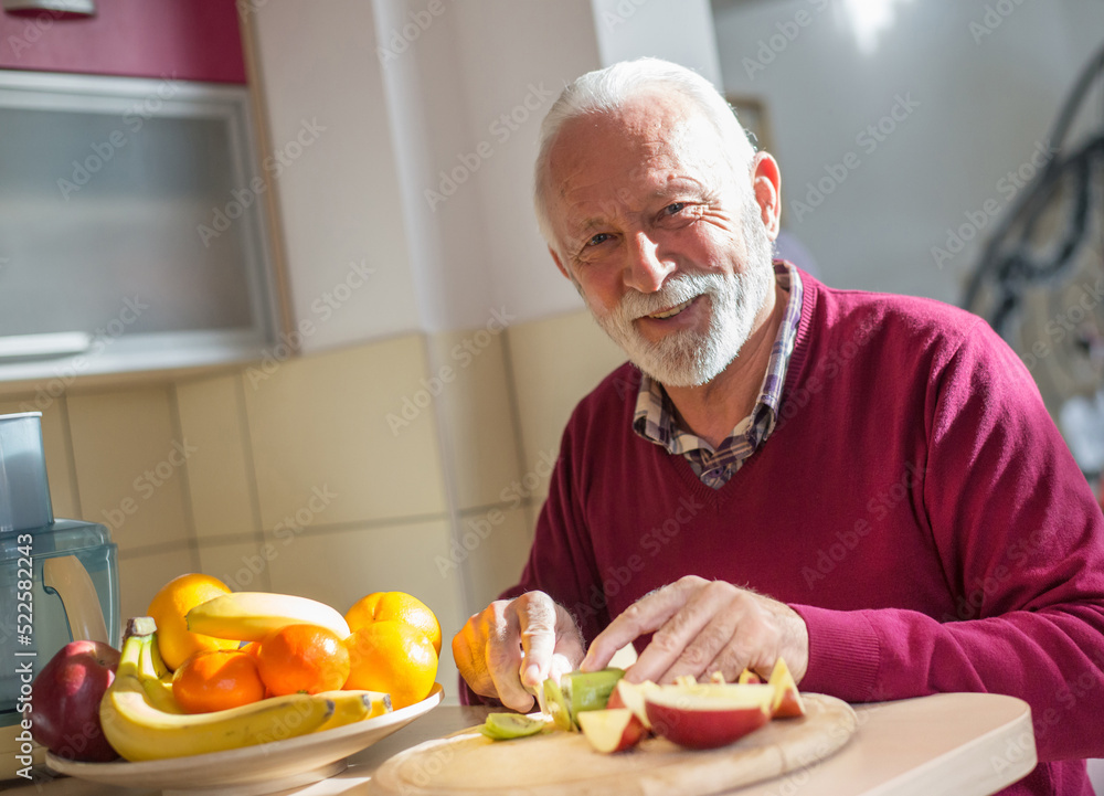 Senior man eating fruits in the kitchen on a sunny day Stock Photo ...