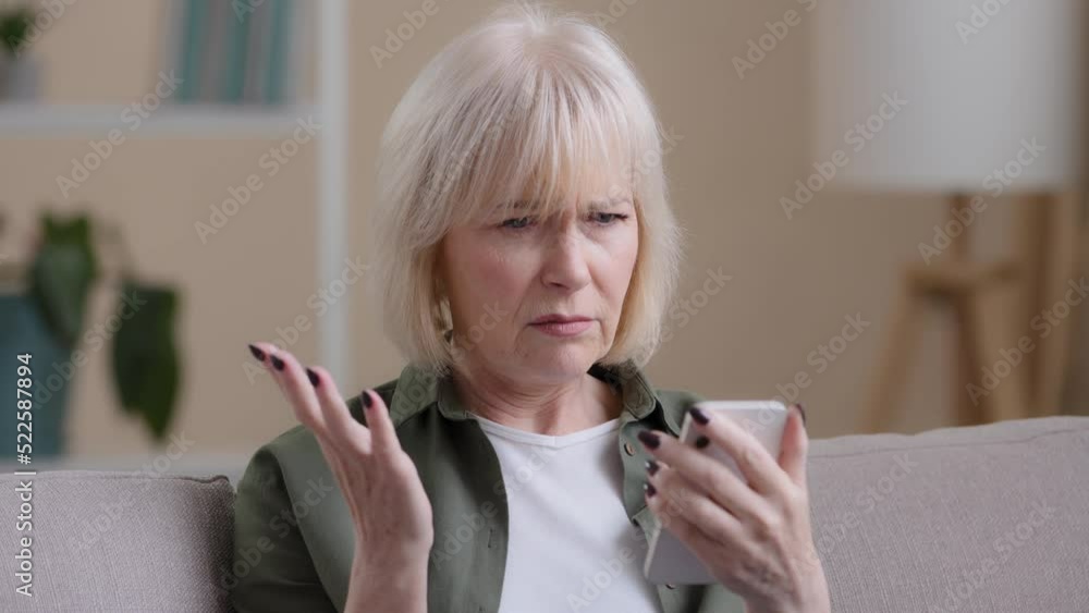 Frustrated senior lady Caucasian elderly woman with phone reads bad ...