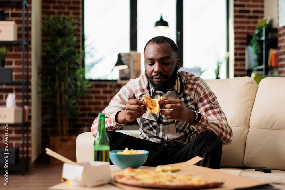 Relaxed person eating slice of pizza in front of television at home ...