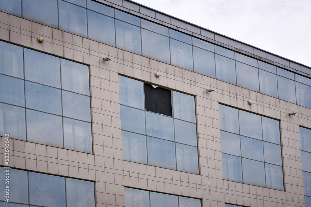 Broken window in glass facade of office building. Broken glass, hole in ...