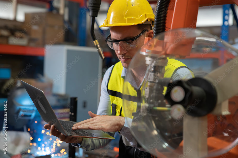 Engineer wearing helmet and hi visible vest working in factory welding ...