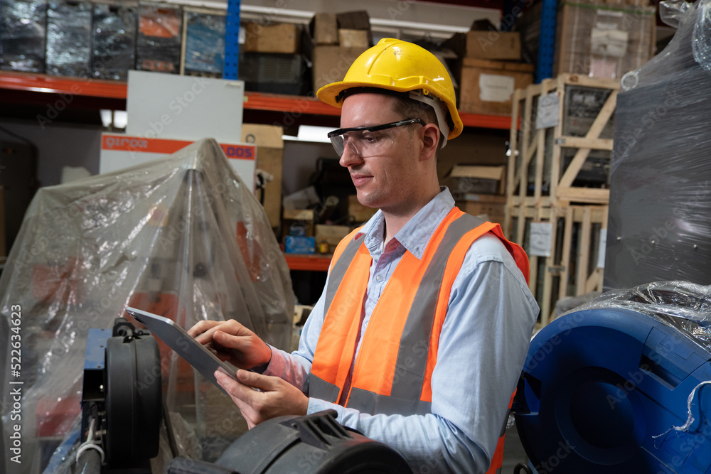 Foto de Engineer in warehouse storage hold tablet to check spare parts ...