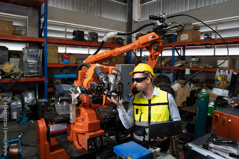 Engineer wearing helmet and hi visible vest working in factory welding ...