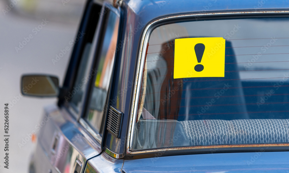 Yellow exclamation mark on the rear window of a car. Designation of an ...