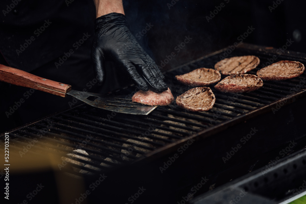 Chef making burger meat at the open air restaurant grill. Festival food ...