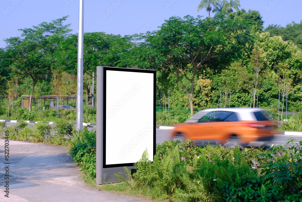 Advertising billboard by the road, with passing speeding car in motion ...