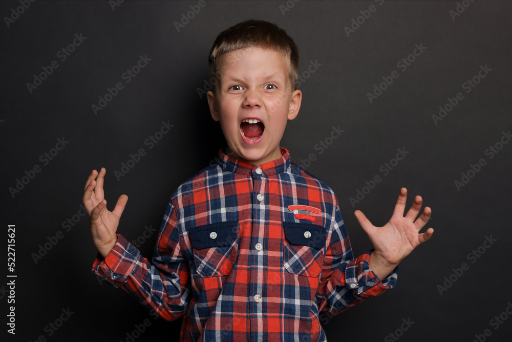 Angry little boy screaming on black background. Aggressive behavior ...