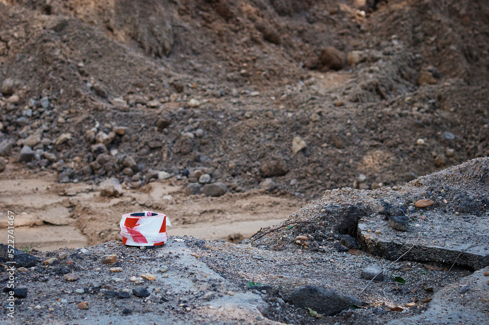 A roll of striped red and white warning tape on a background of earth ...