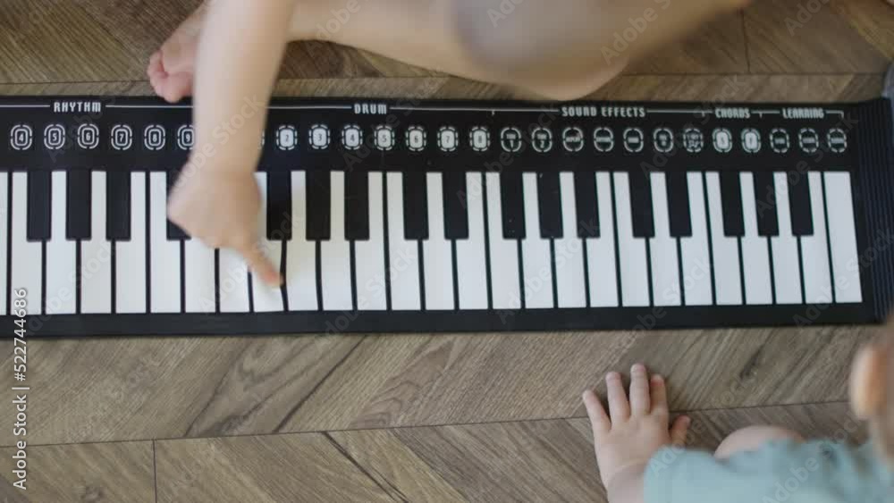 high angle baby hands learning playing electronic piano on floor. top ...