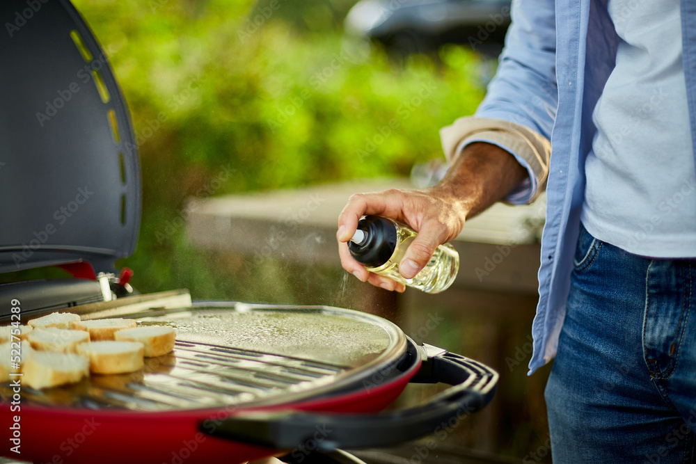 Prepare breakfast with bread, roasting bruschetta and man spraying oil ...