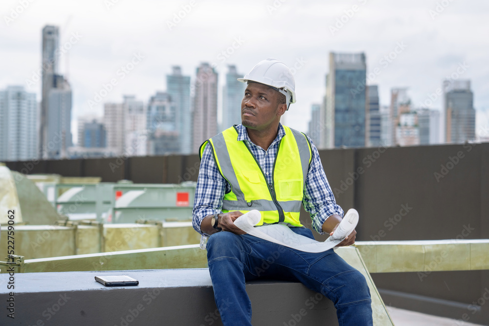 African male civil engineer inspects a commercial building construction ...