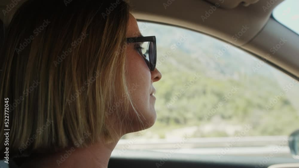 Young woman driving car and looking around at road traffic of green ...