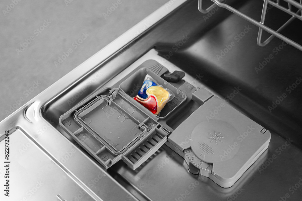 Dishwasher. Dishwashing capsules. Open dishwasher with clean dishes in a white kitchen ...