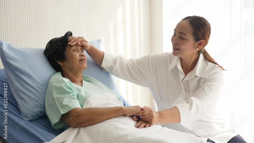 Medium shot of Asian woman visiting sick senior female inpatient who is ...