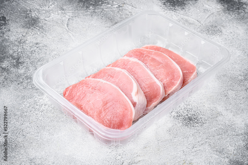Pork meat. Fresh pork steaks, in plastic pack container, on gray stone ...