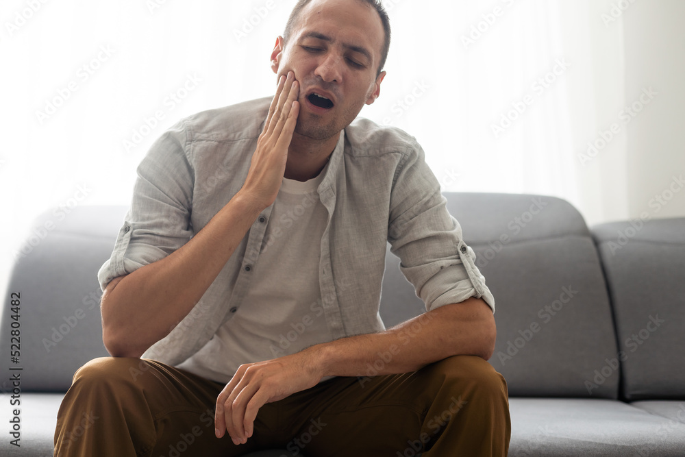 Male patient with severe toothache touching cheek with grimace of pain ...