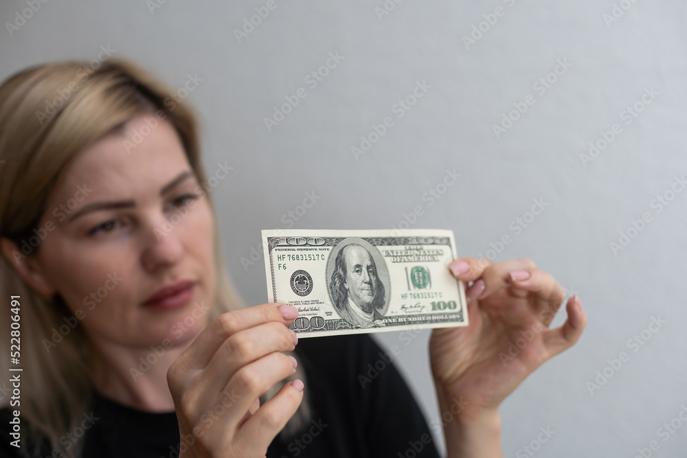 Checking counterfeit money light. 100 dollars against the window in his ...