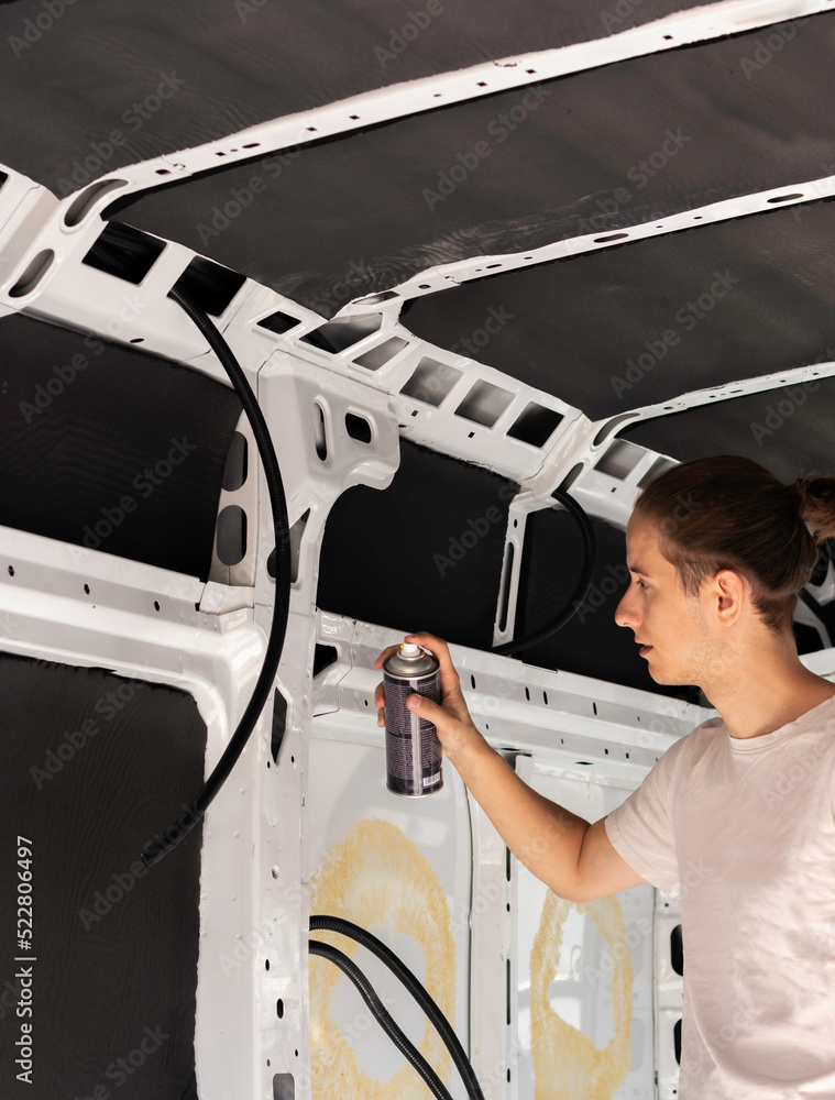 Vertical view of young man using a spray paint bottle to paint the ...