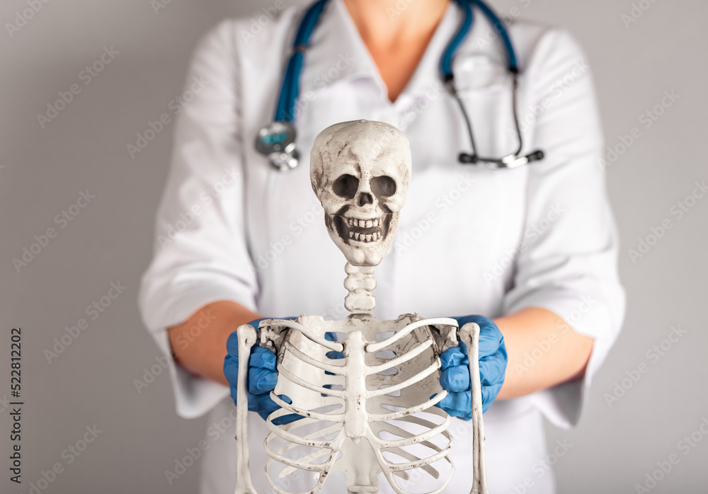 Doctor showing human skeleton. Woman in lab coat with stethoscope ...