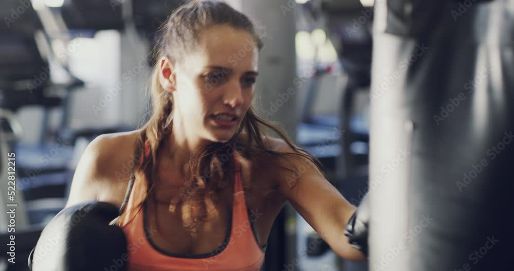 Fitness, health and an intense athlete boxing a punching bag at a ...