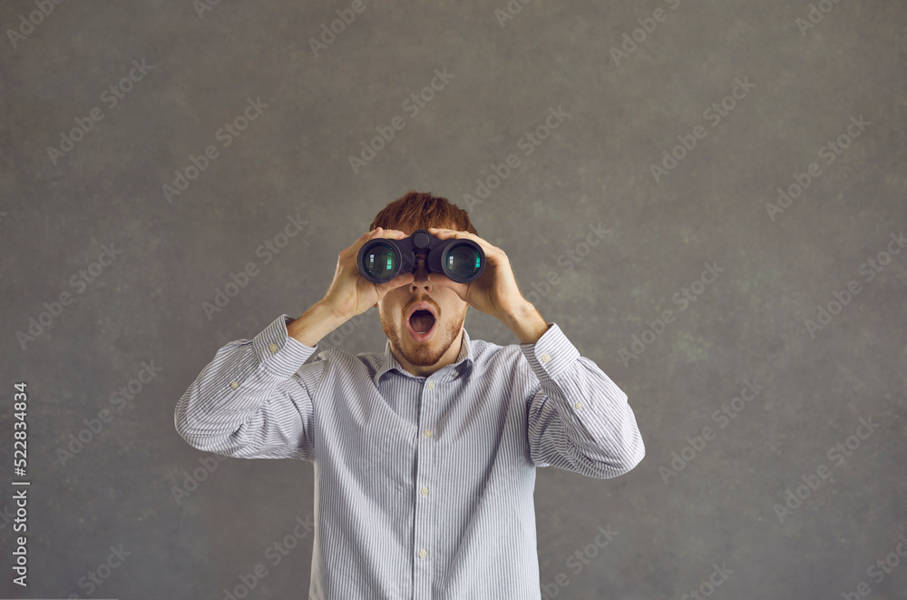 WOW. Studio portrait of funny surprised man holding binoculars and ...