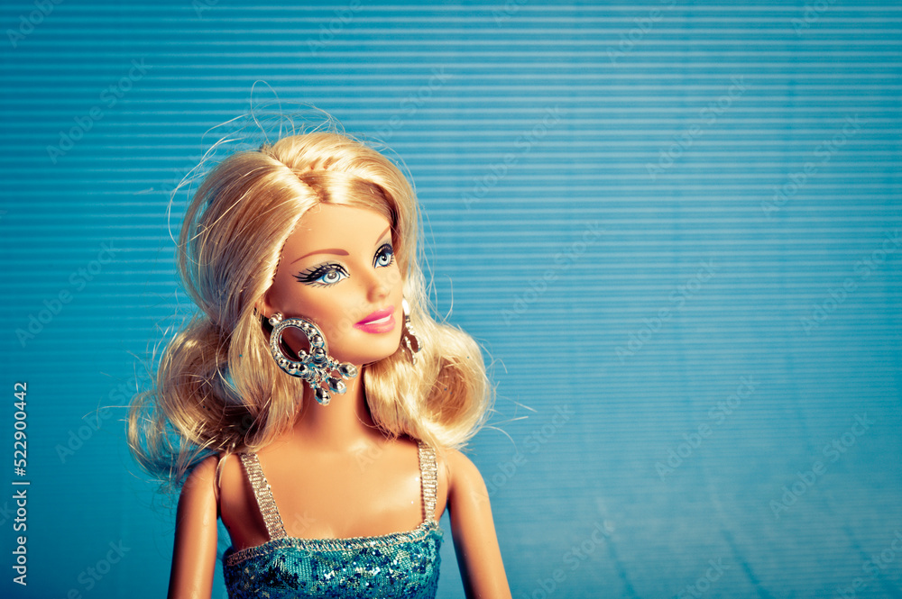 blond Barbie doll in blue dress over blue background Stock Photo ...