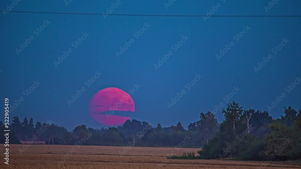 Full blood moon rising over a countryside field as twilight turn to ...