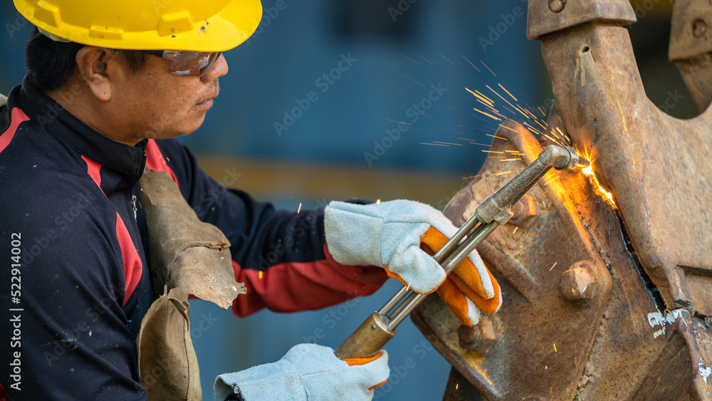 Industrial worker metal cutting with acetylene torch at factory welding ...