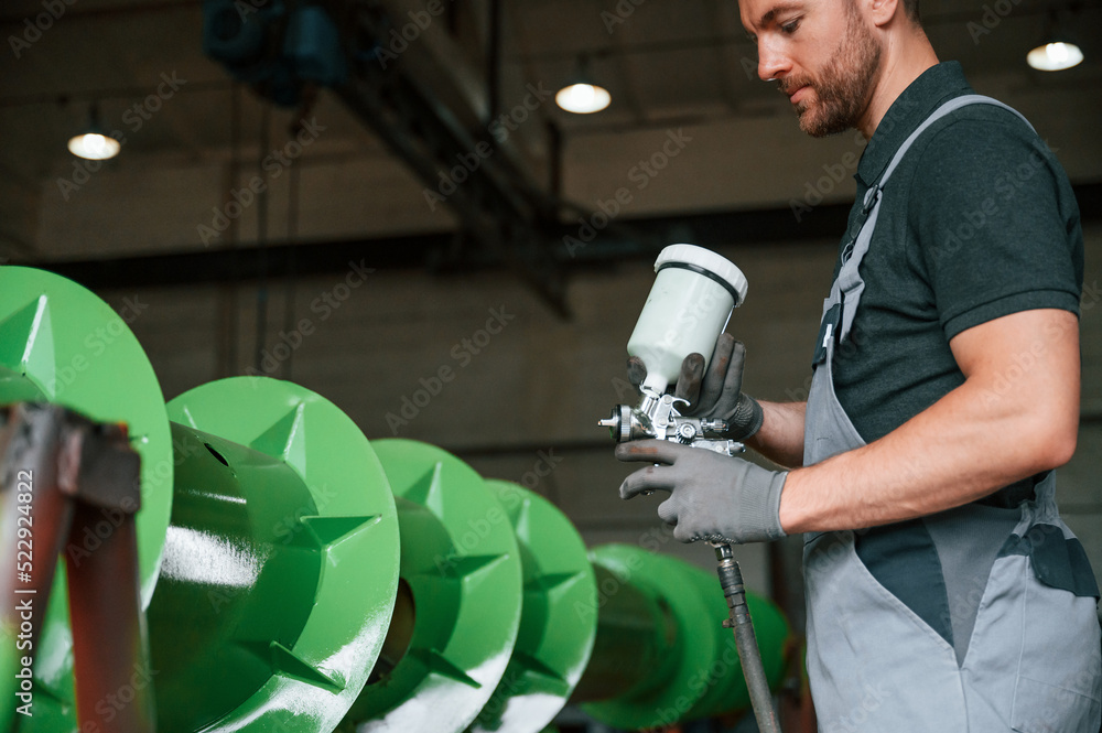 Painting details to green color. Man in uniform is in workstation ...