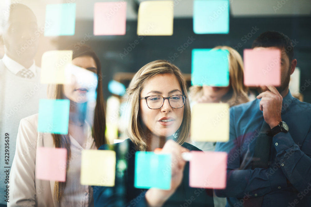 Talking team leader writing on sticky notes while planning, innovating ...