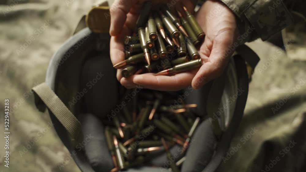 a soldier holds bullets for his machine gun and pours them into his ...