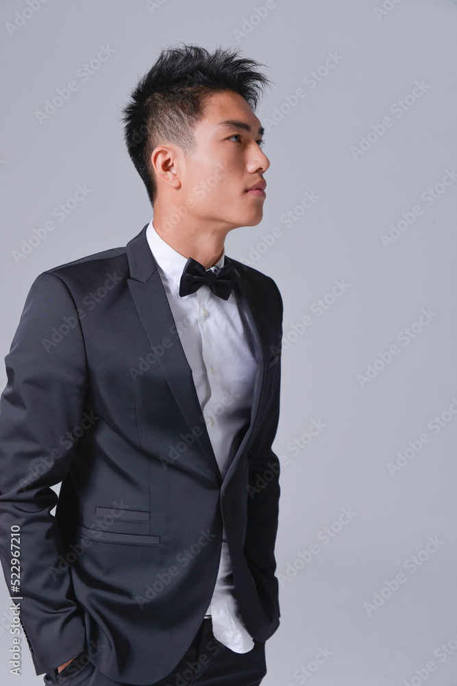 Handsome fashion model. elegant man wear formal black suit with bow tie ...