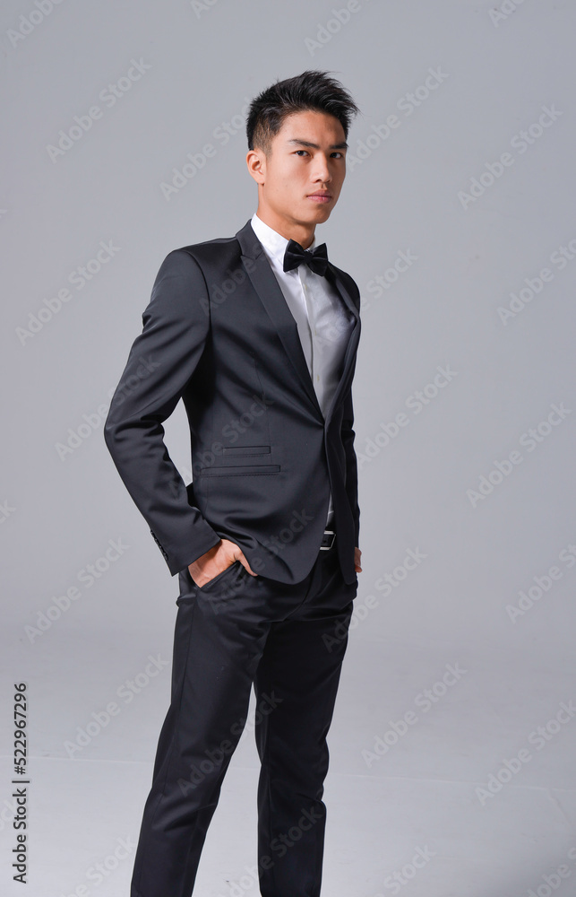 Handsome fashion model. elegant man wear formal black suit with bow tie ...