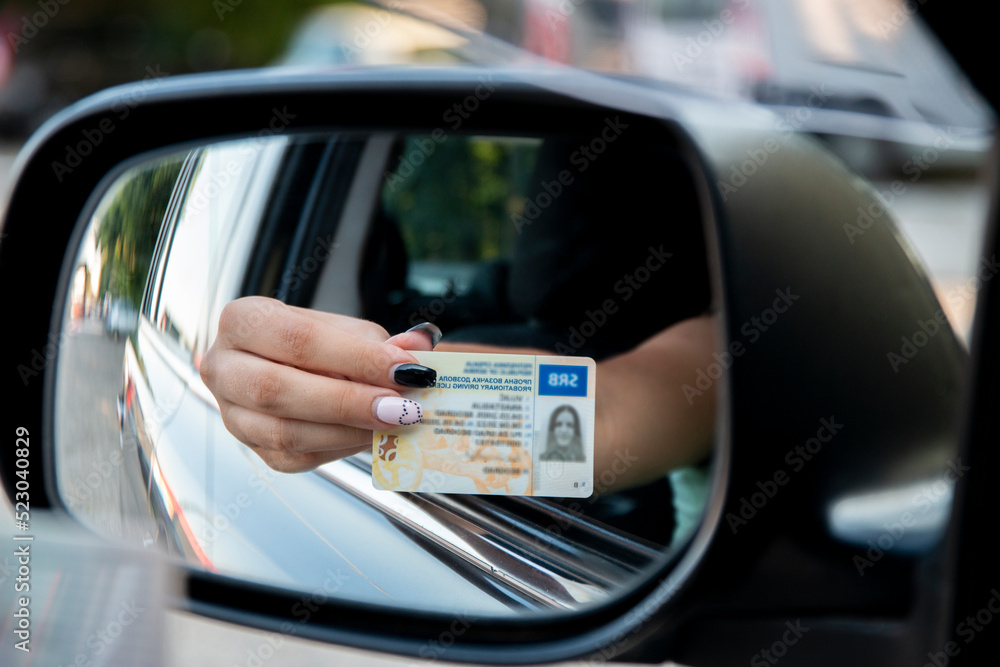 Teenager girl showing his driver's license in the car window after ...