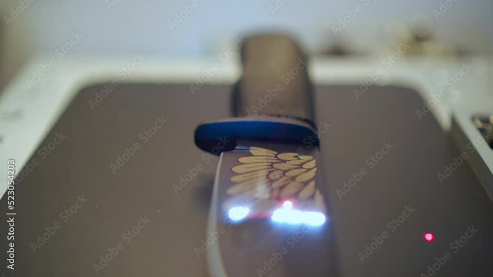 Hunting black knife on laser machine work platform in engraving process ...