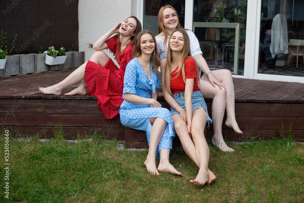 Group of young smiling gorgeous barefoot women sitting on wooden ...