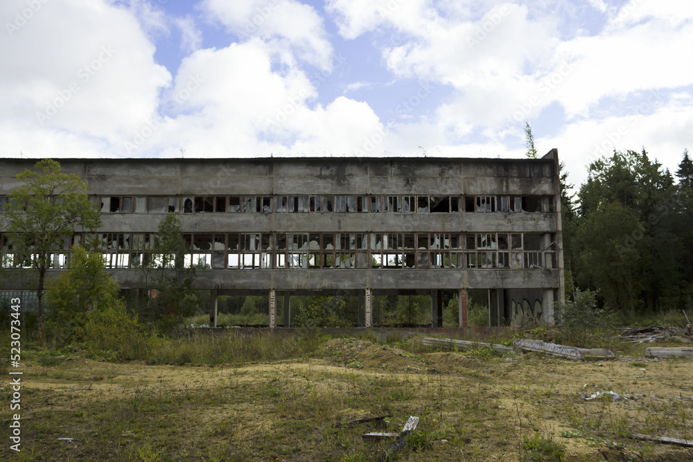 ruined industrial building on stilts with a broken wall of glass ...